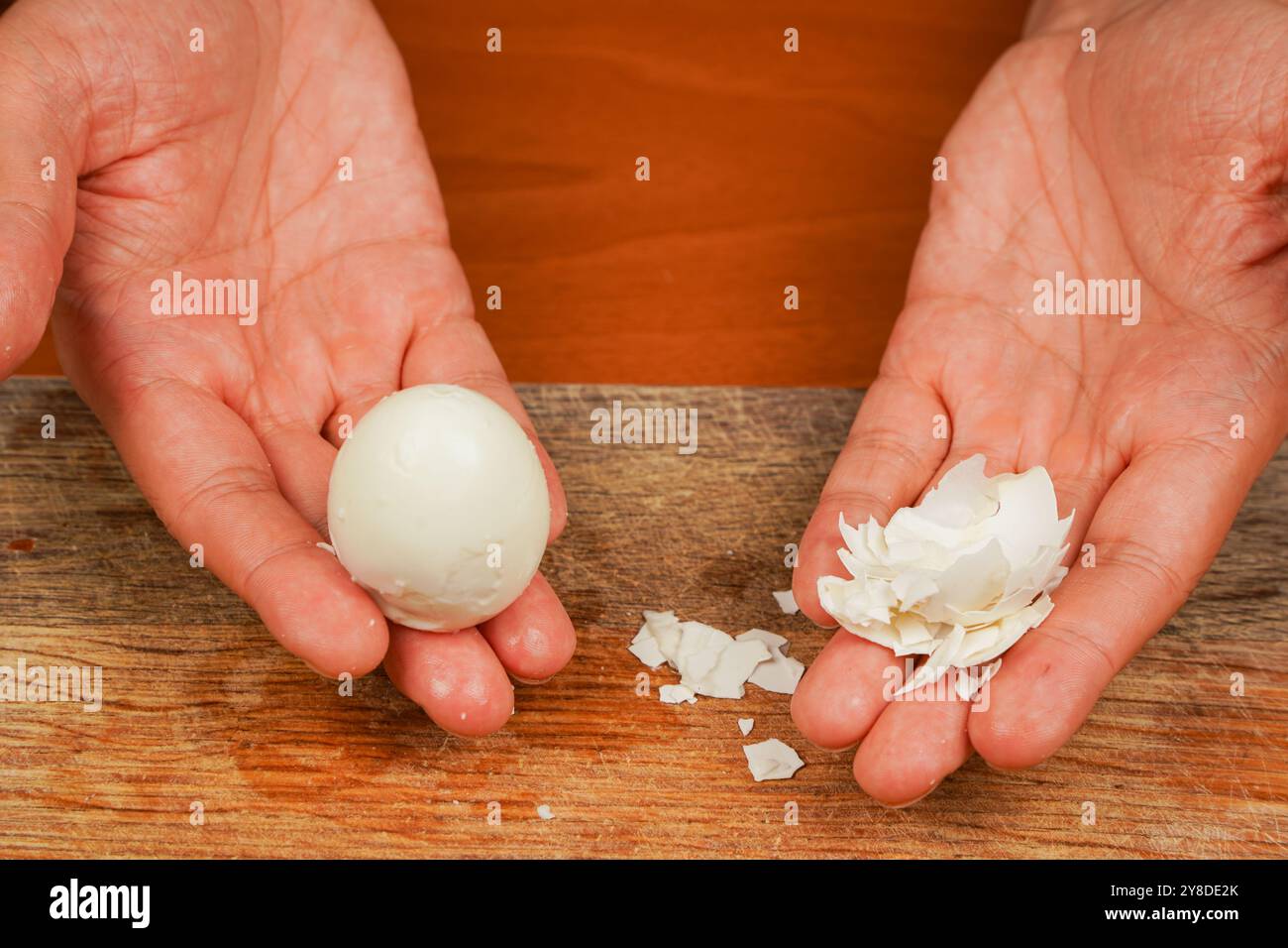 Man holding chicken egg over wooden board. Boiled egg. Cleaned egg from ...