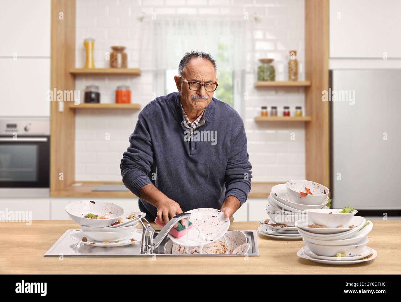 Grumpy mature man washing dishes in a kitchen sink Stock Photo - Alamy