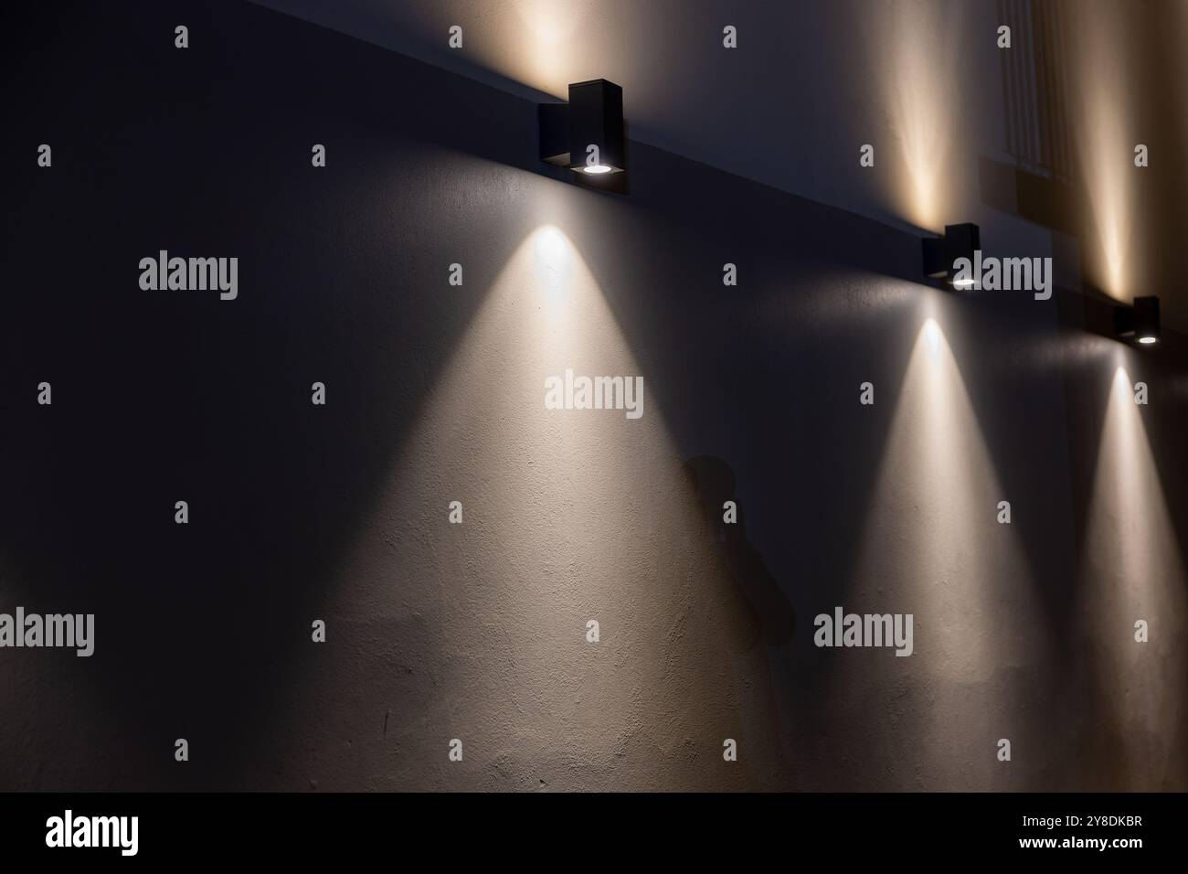 Wall-mounted spotlights casting light beams on a textured wall Stock ...