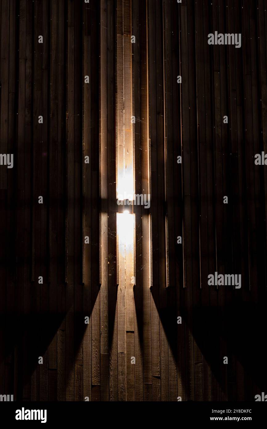 A wooden wall with vertical planks illuminated by a central light ...
