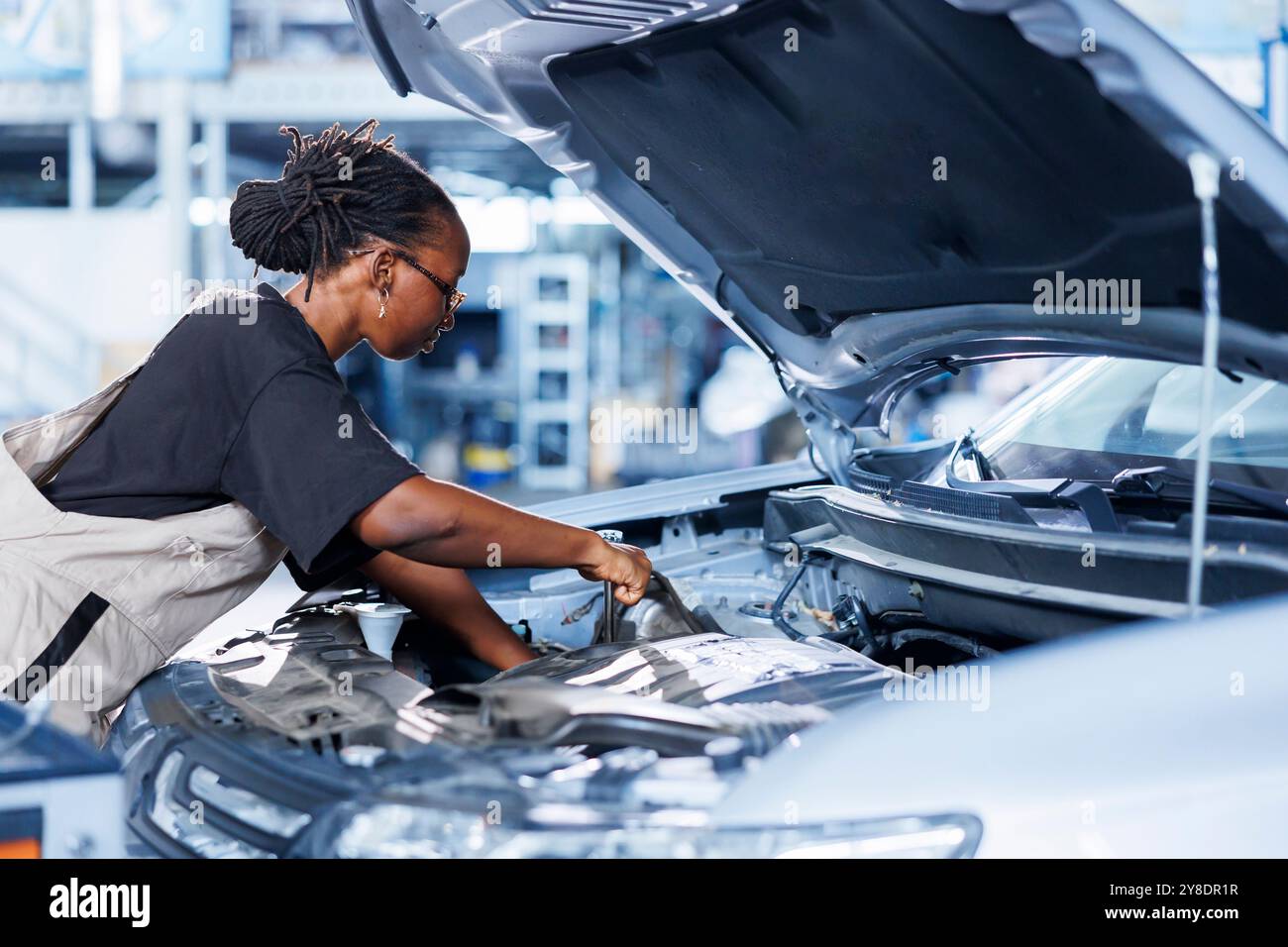 Auto repair shop mechanic expertly examines car engine using advanced mechanical tools, ensuring ...