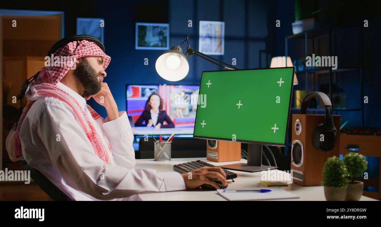 Arabic man looking at chroma key computer screen while working from ...