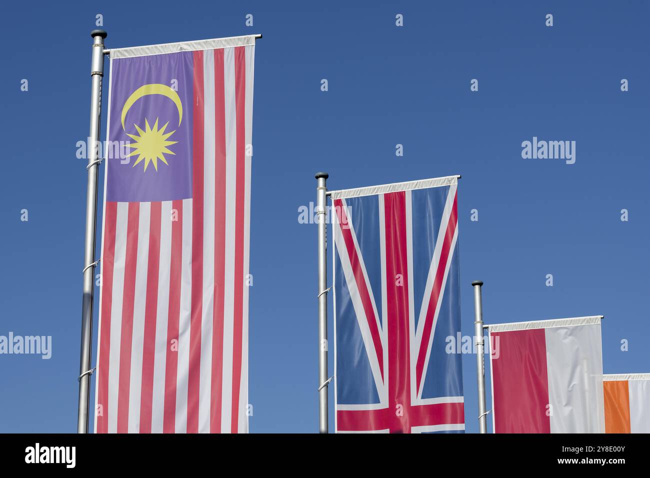 Several flags of different countries fly side by side under a clear ...
