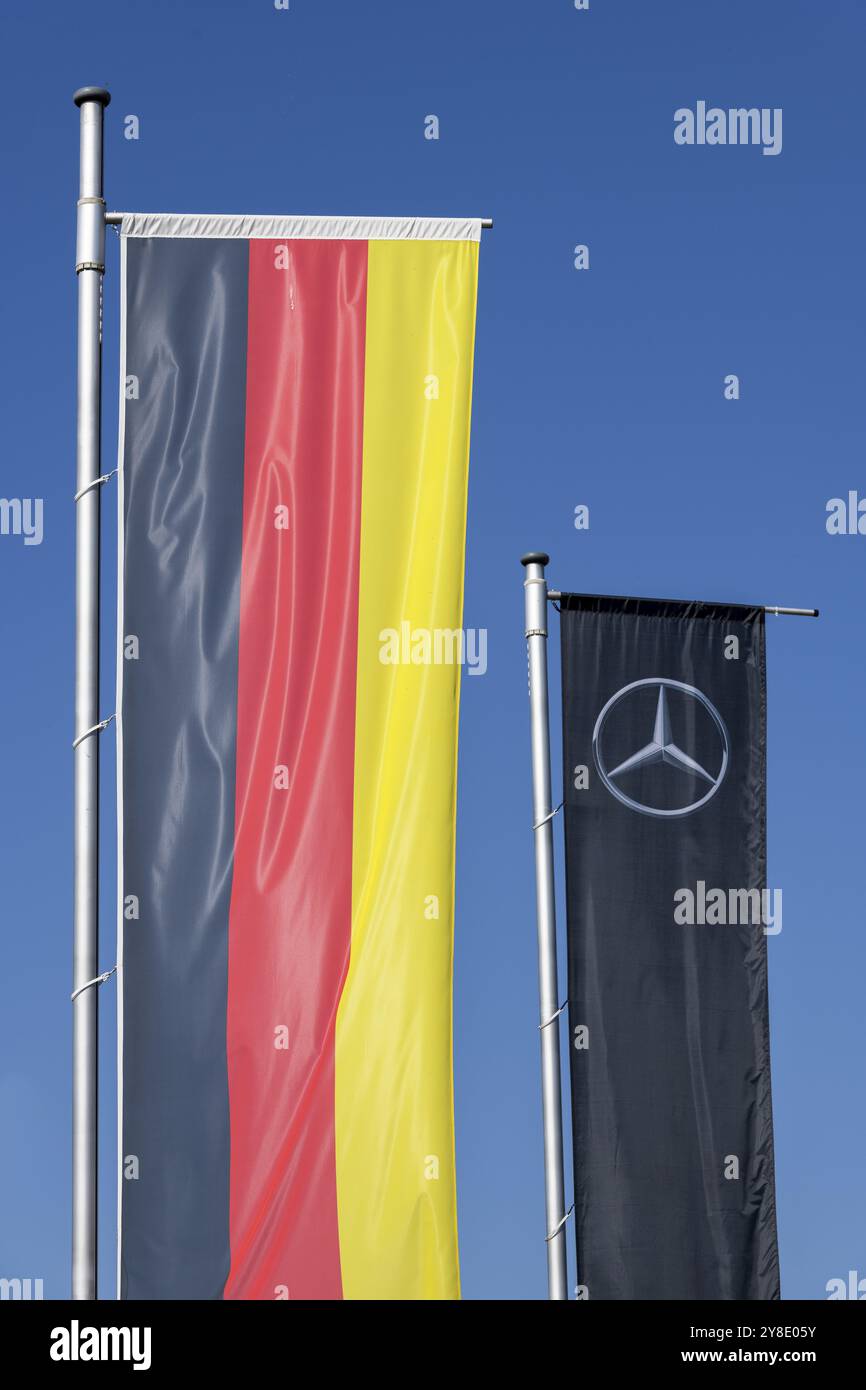 Two flags against a blue sky, one showing the German national colours ...