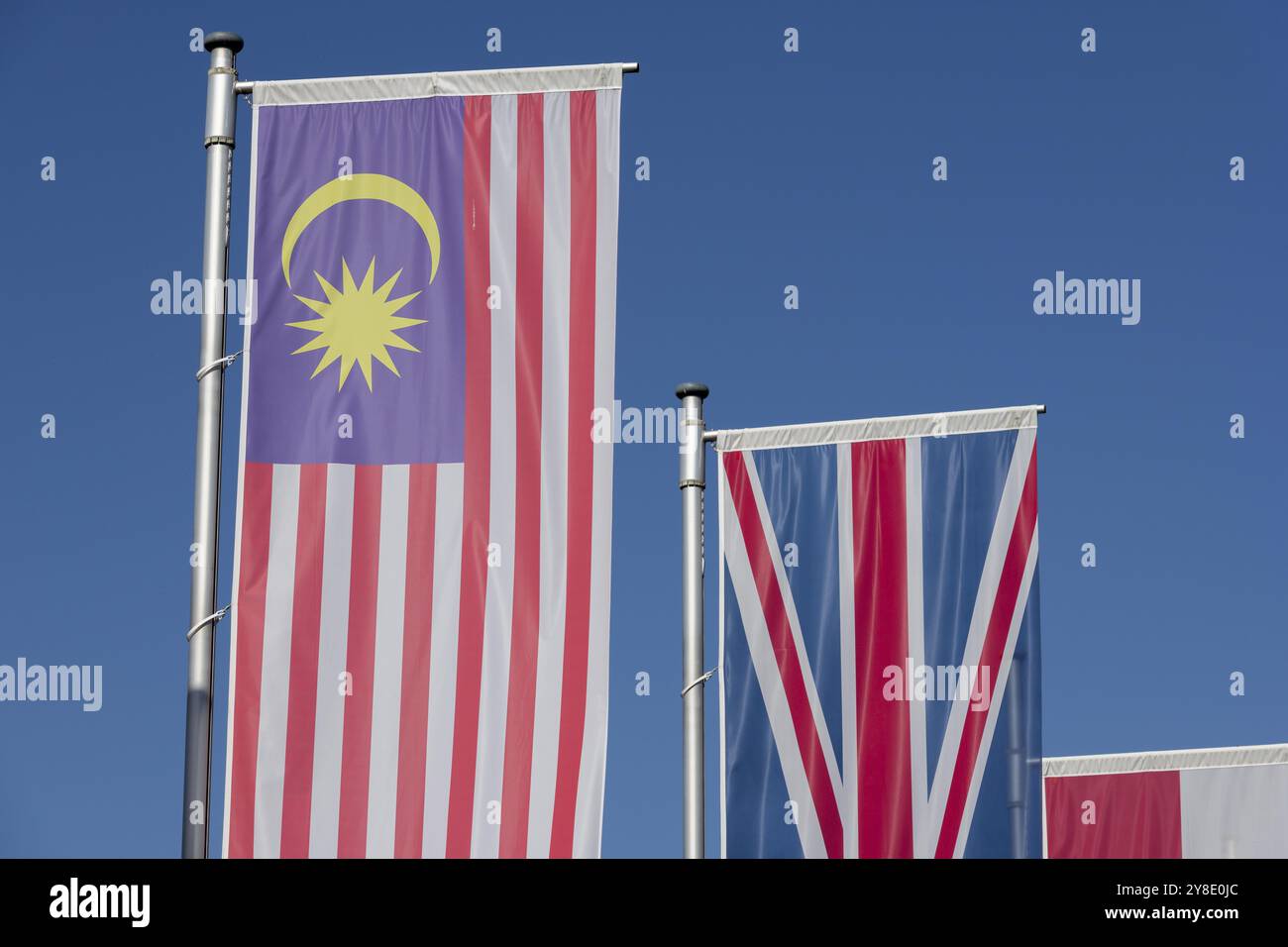 Several flags of different countries fly side by side under a clear ...