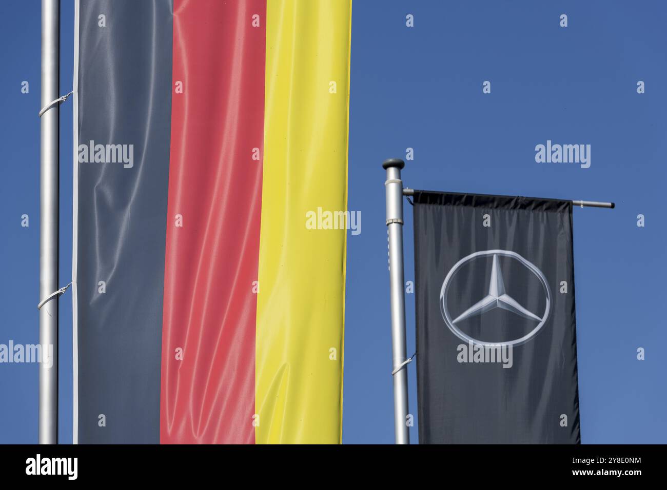 Two flags against a blue sky, one showing the German national colours ...