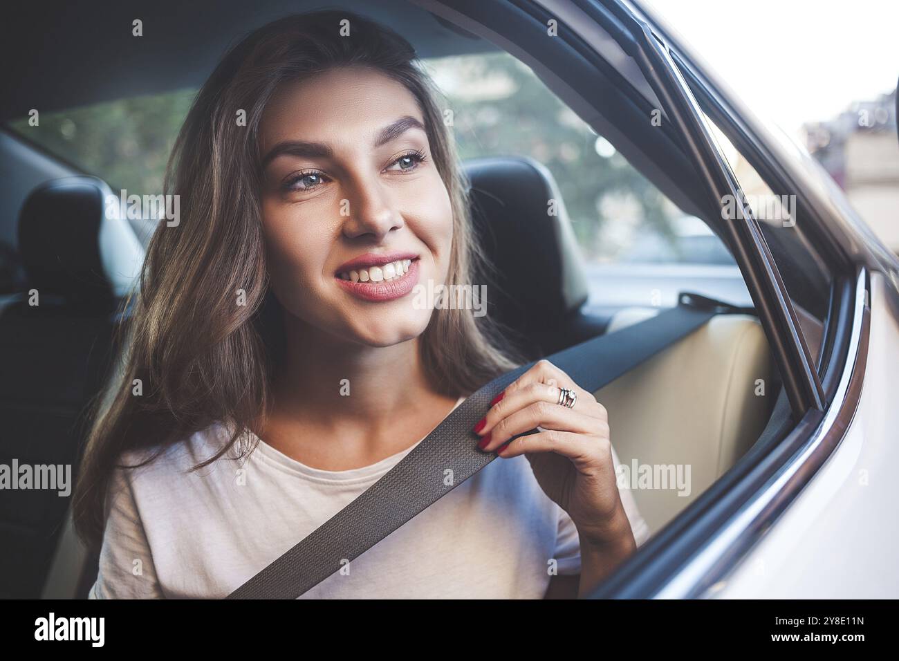 Beautiful woman with phone smiling while sitting on the back seat in ...