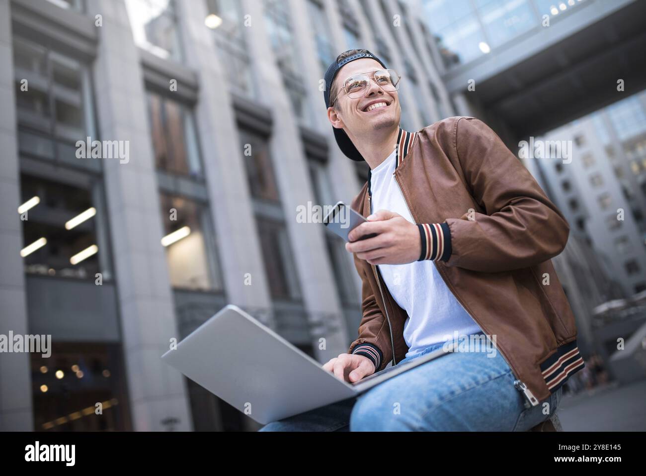Happy handsome student looking at computer screen while typing ...