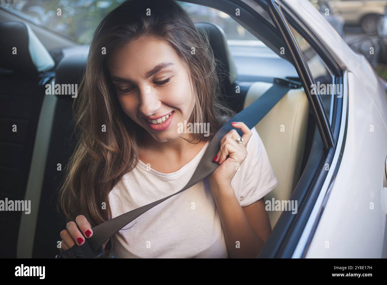 Beautiful woman with phone smiling while sitting on the back seat in ...