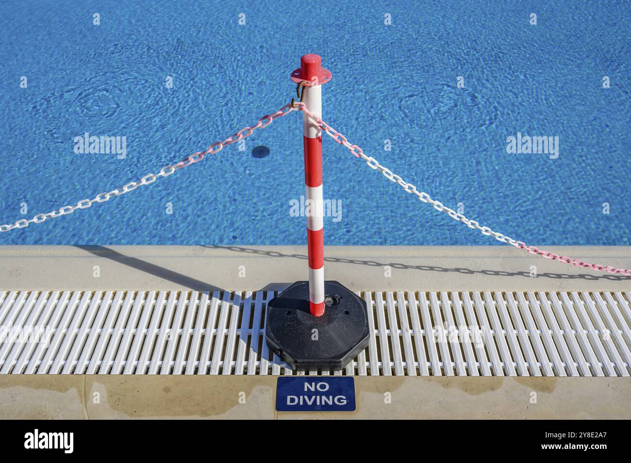 Barrier chain with no diving sign at the edge of a blue swimming pool ...