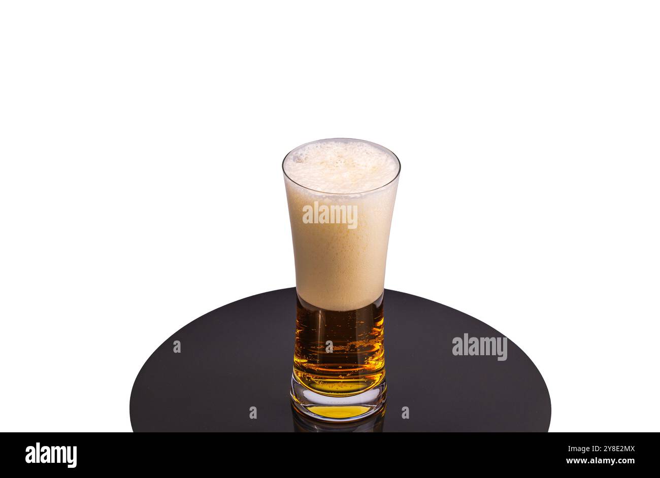Glass of cold beer with frothy foam head on top, standing on round ...