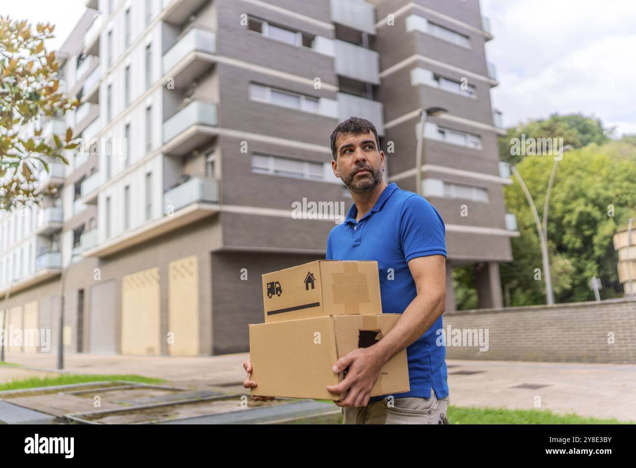 Caucasian mature male Amazon delivery person carrying box in the city ...