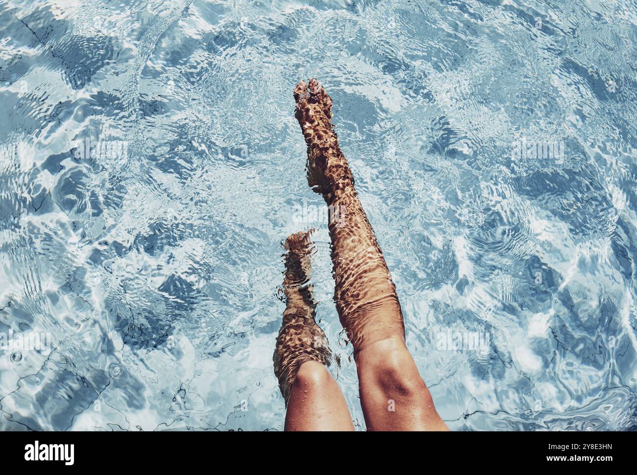 Two legs protrude from the blue pool water, calming beauty Stock Photo ...