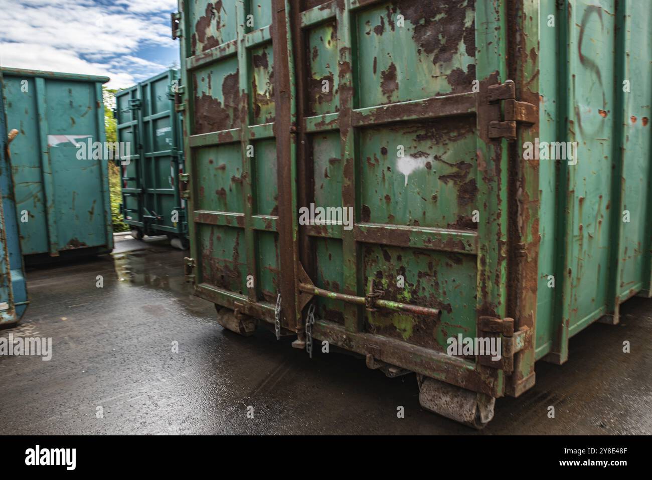 Large green containers with rust stains stand on a rain-soaked ...