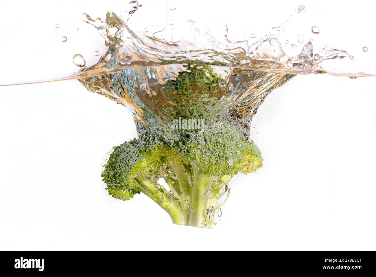An abstract photo of a head of broccoli being dropped into clear water ...