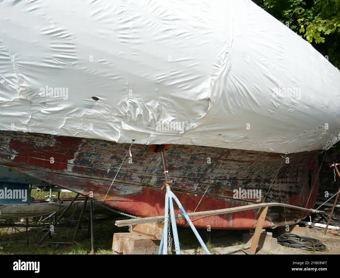 Old weathered sailboat in dry dock with tarp covering Stock Photo - Alamy
