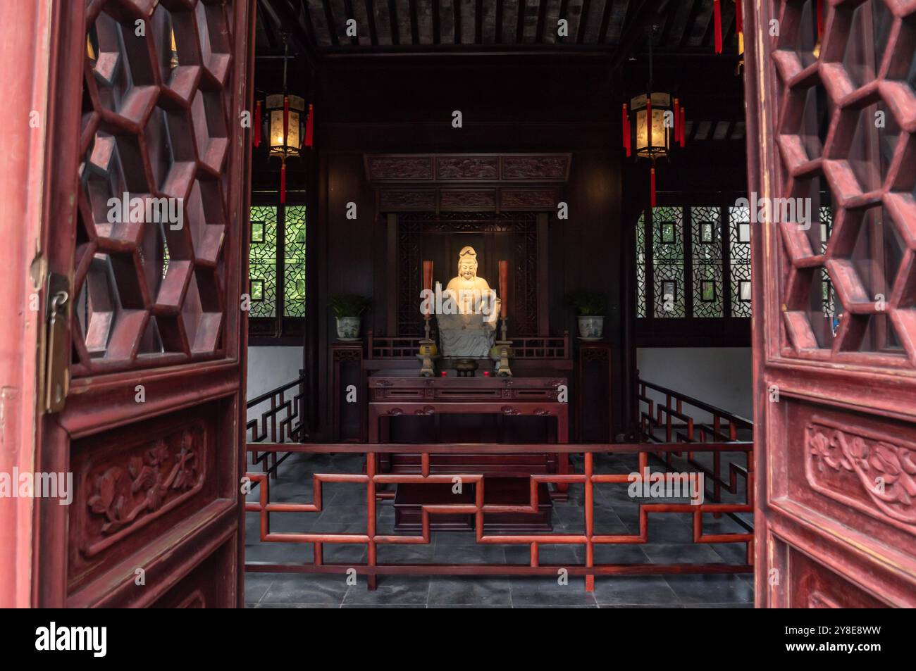 Traditional Chinese interior with a statue and ornate wooden doors ...