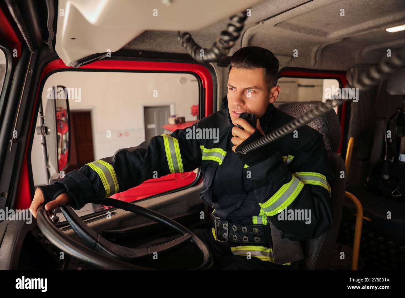 Firefighter using radio set while driving fire truck Stock Photo - Alamy