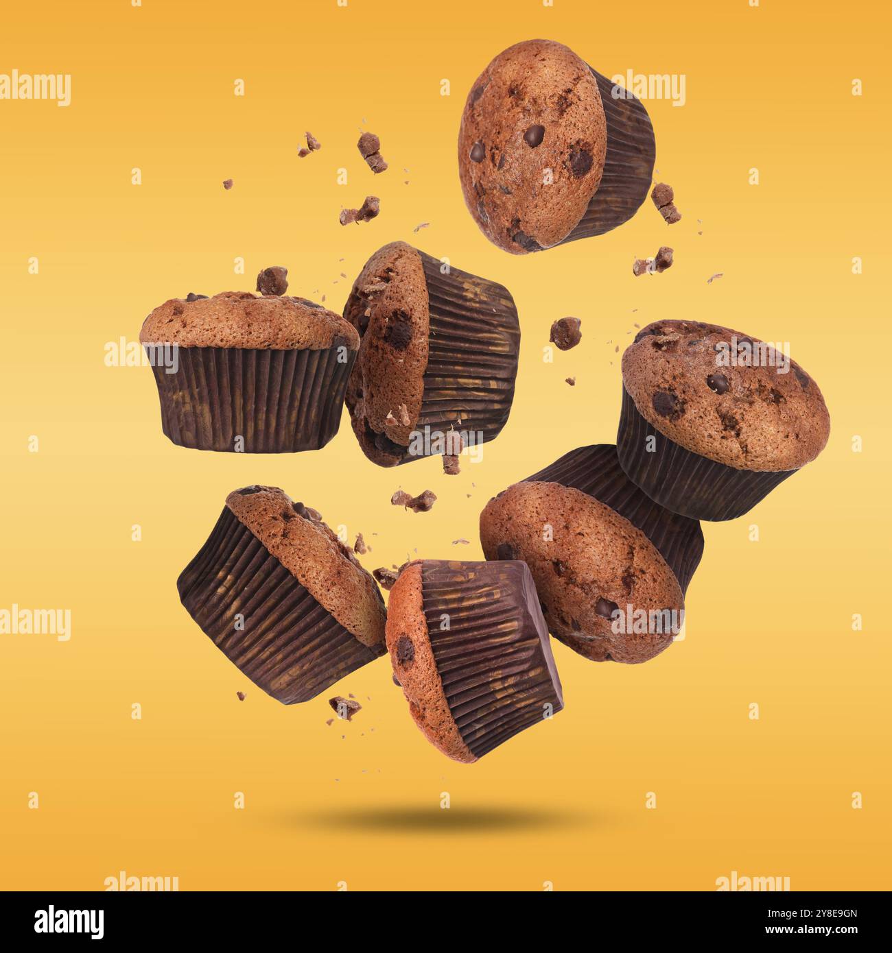 Delicious chocolate muffins and crumbs falling on golden background ...