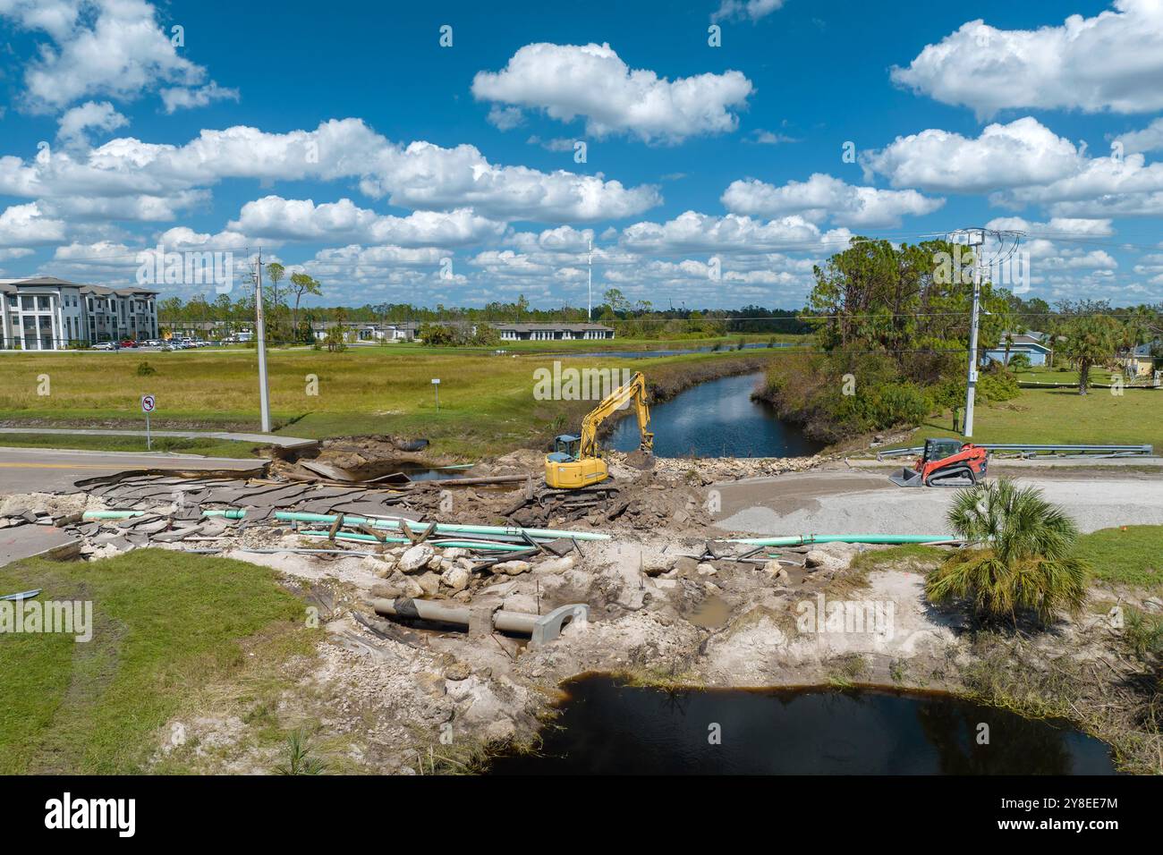 Road construction. Excavator repairing destroyed bridge after hurricane ...