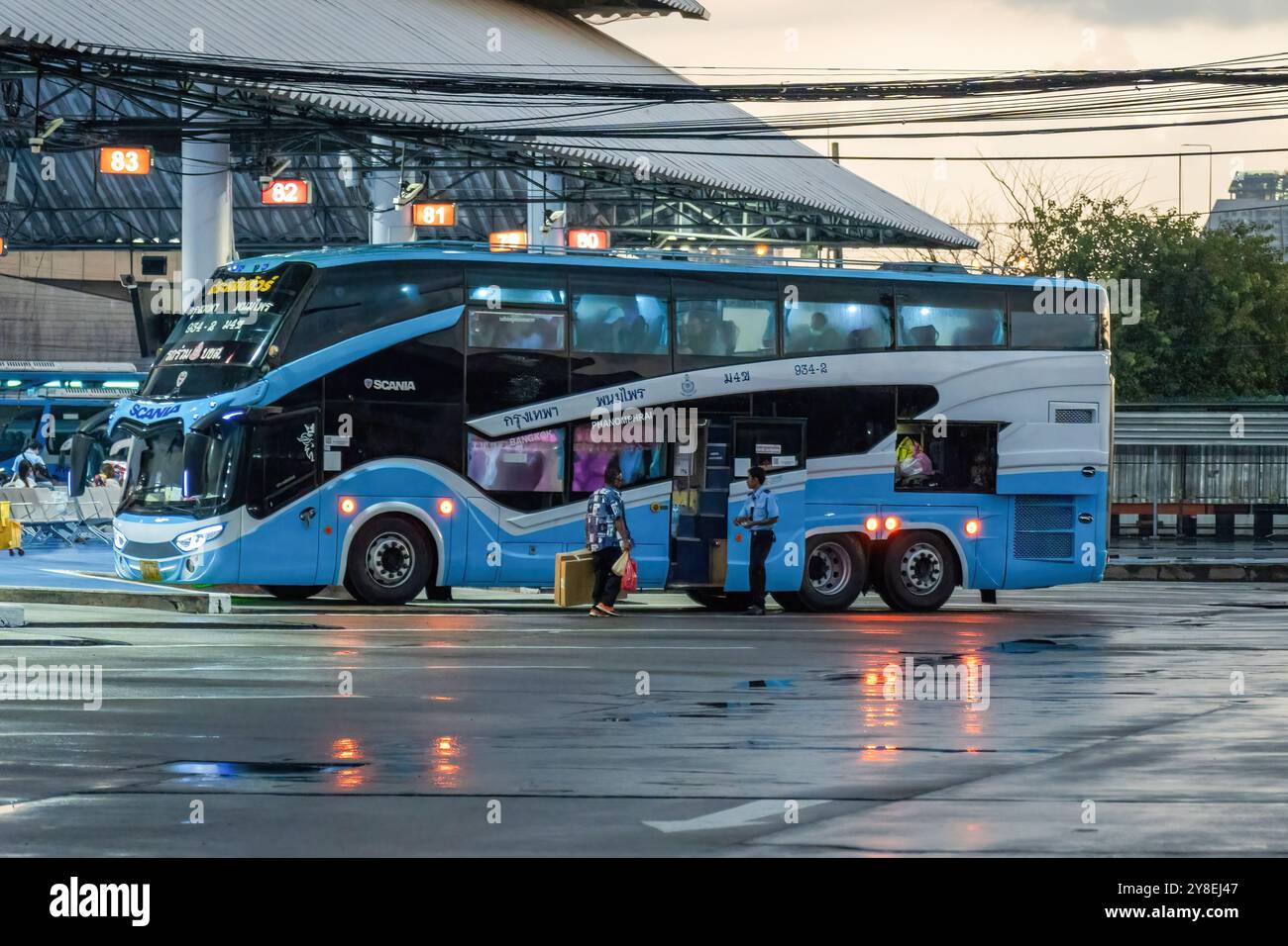 A view of a double-decker bus at dusk, with a passenger going to get in ...