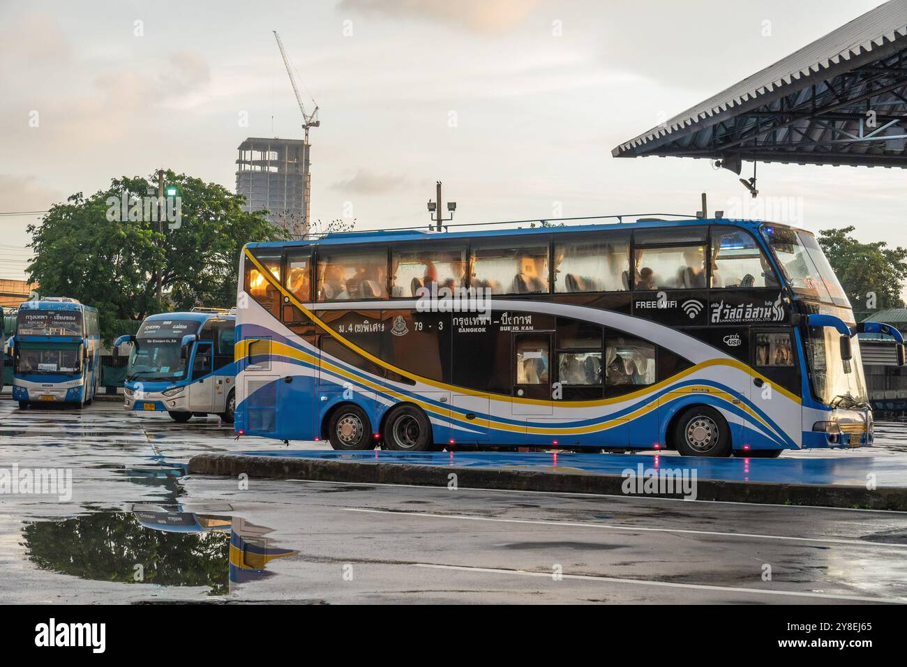 A view at sunset of a double-decker bus with inside passengers waiting ...