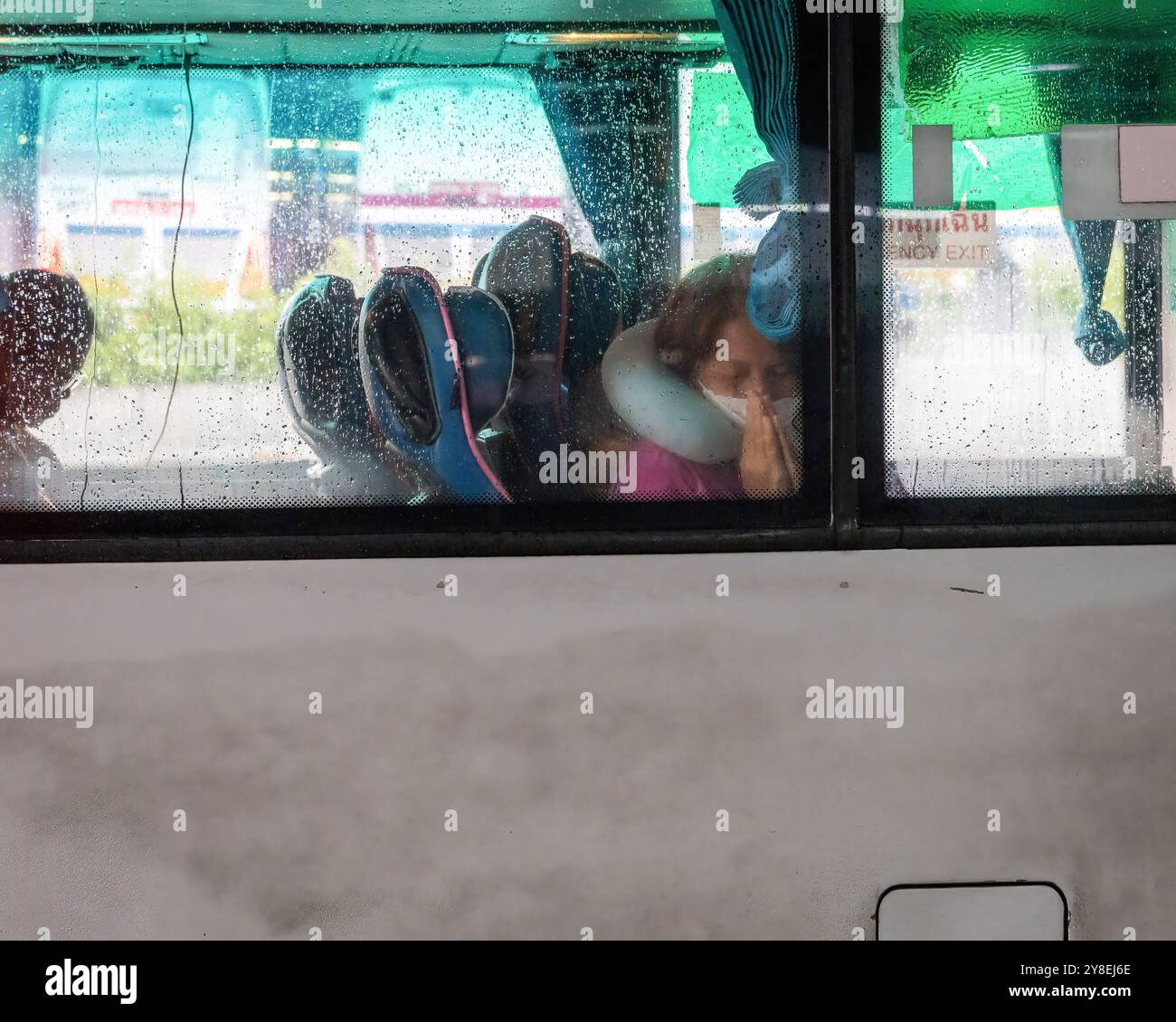 A close-up of a woman who is praying inside a double-decker bus, before ...