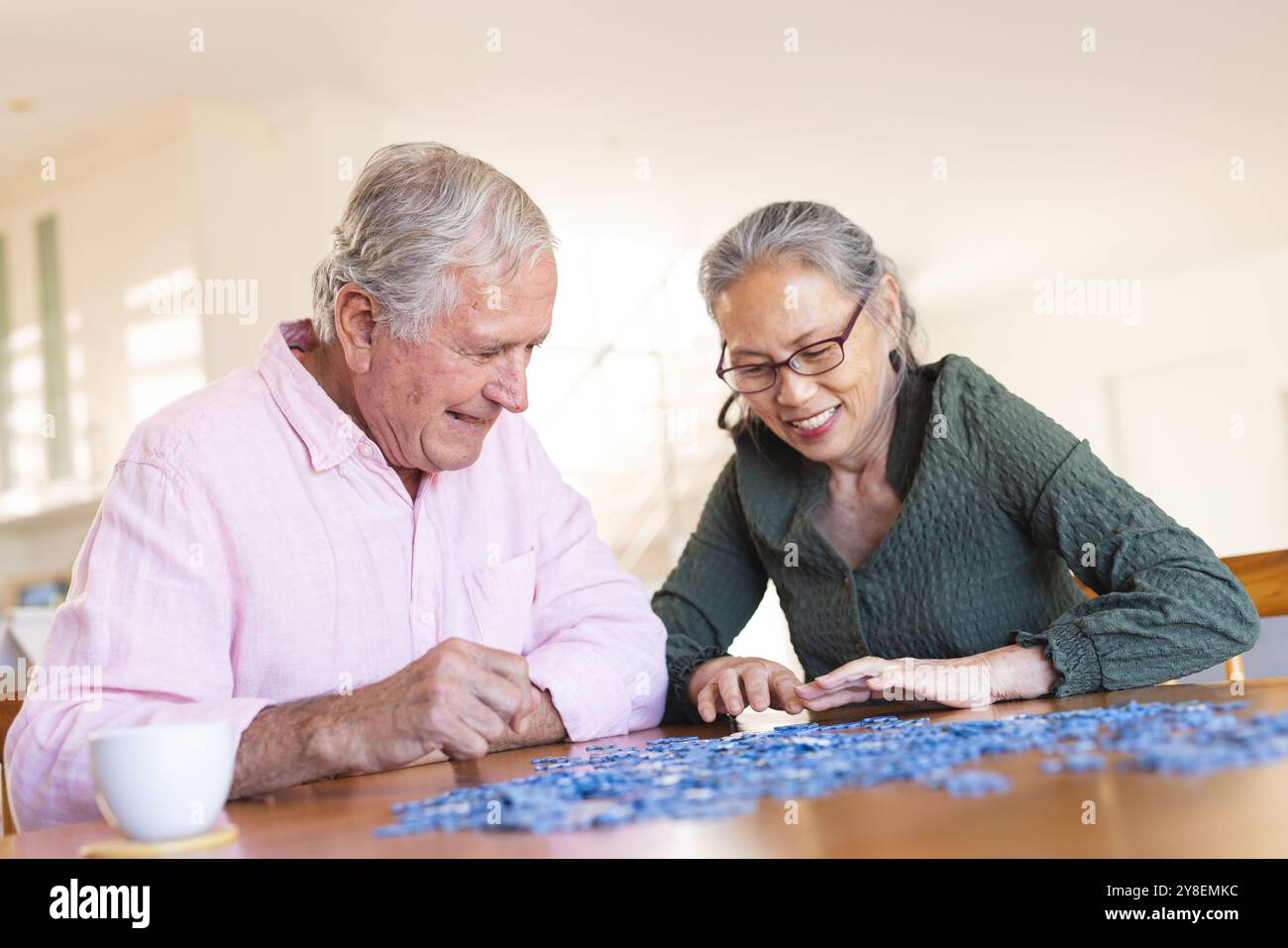 Happy senior diverse couple sitting at table and doing puzzles Stock ...