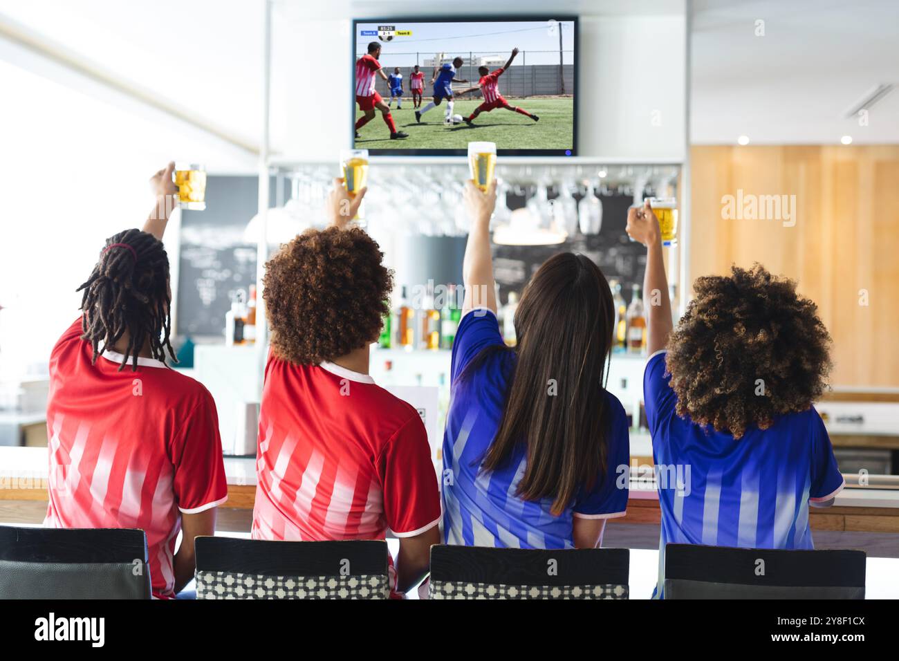 Group of diverse friends watching football match together and drinking ...