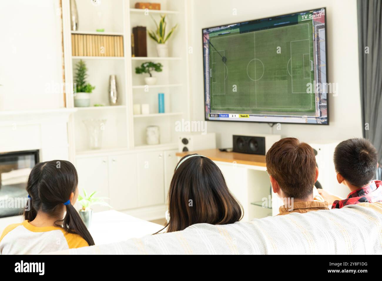 Diverse group of children watching football match together and sitting ...