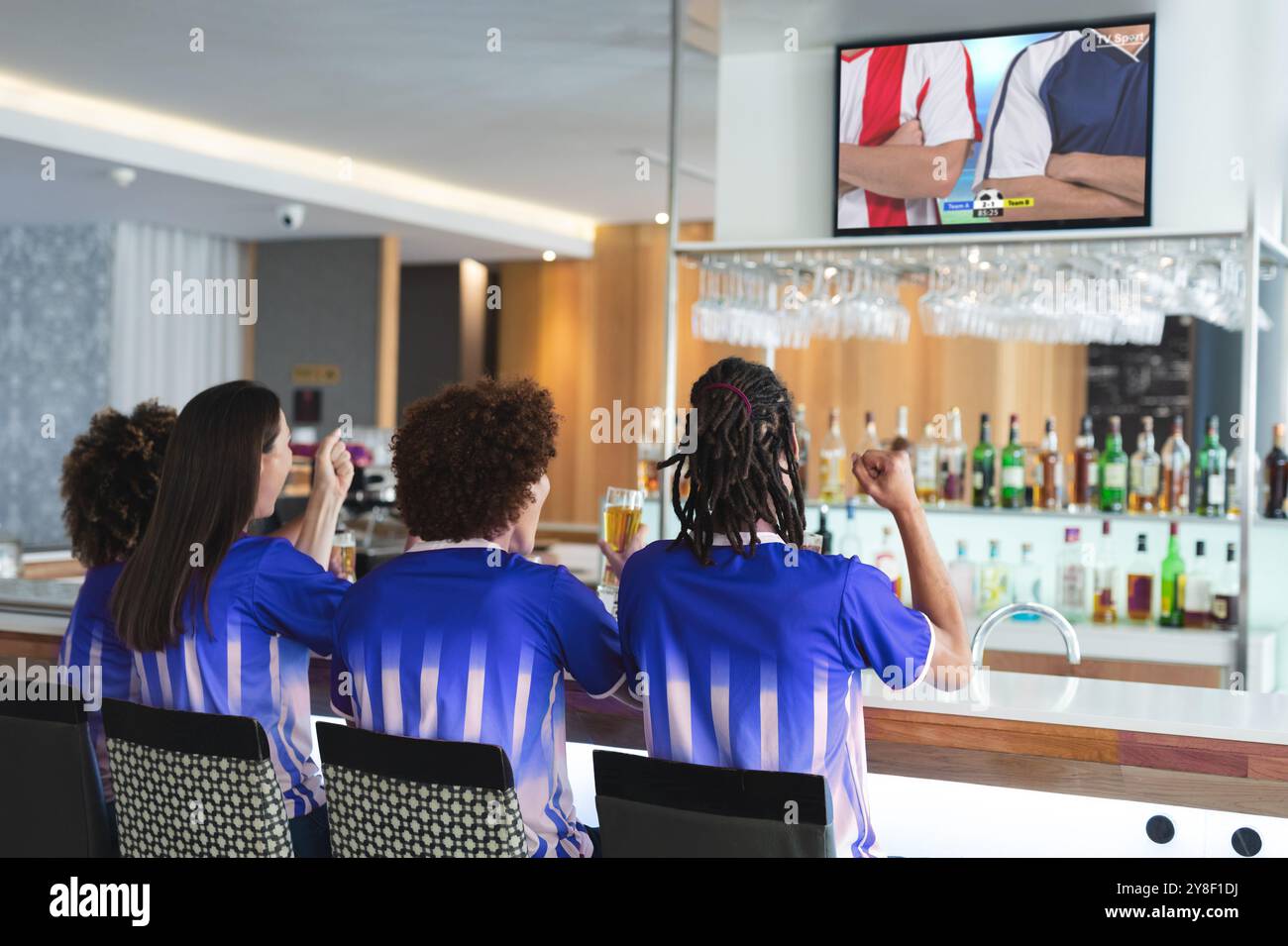Group of diverse friends watching football match together and drinking ...