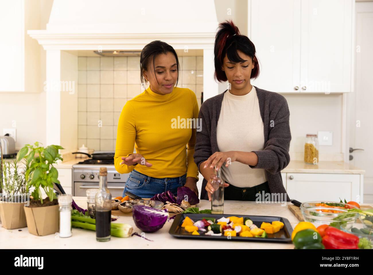 Happy biracial sisters cooking vegetables in kitchen together Stock ...