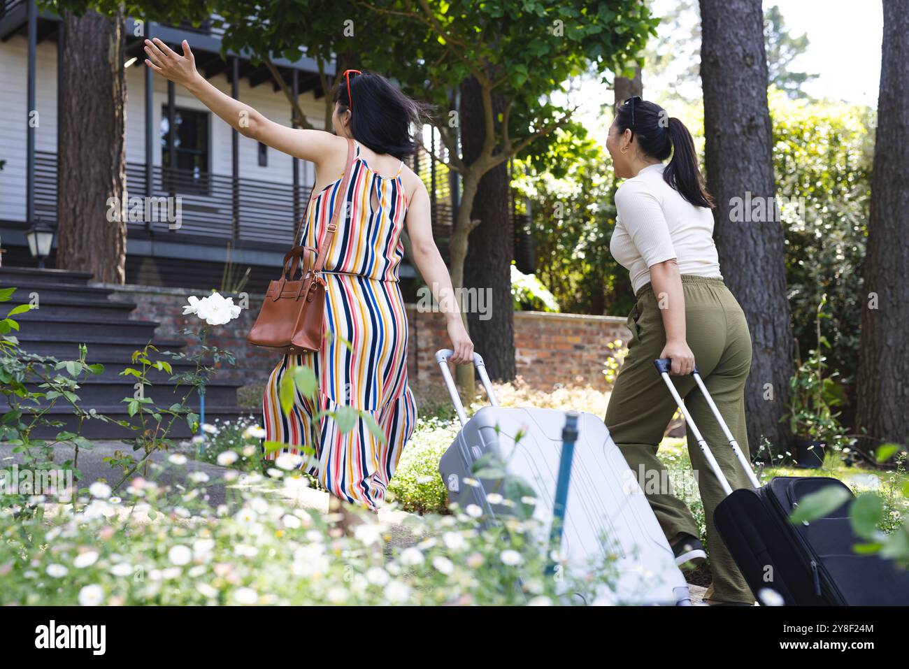 Happy asian female friends walking with luggage in garden at home Stock ...