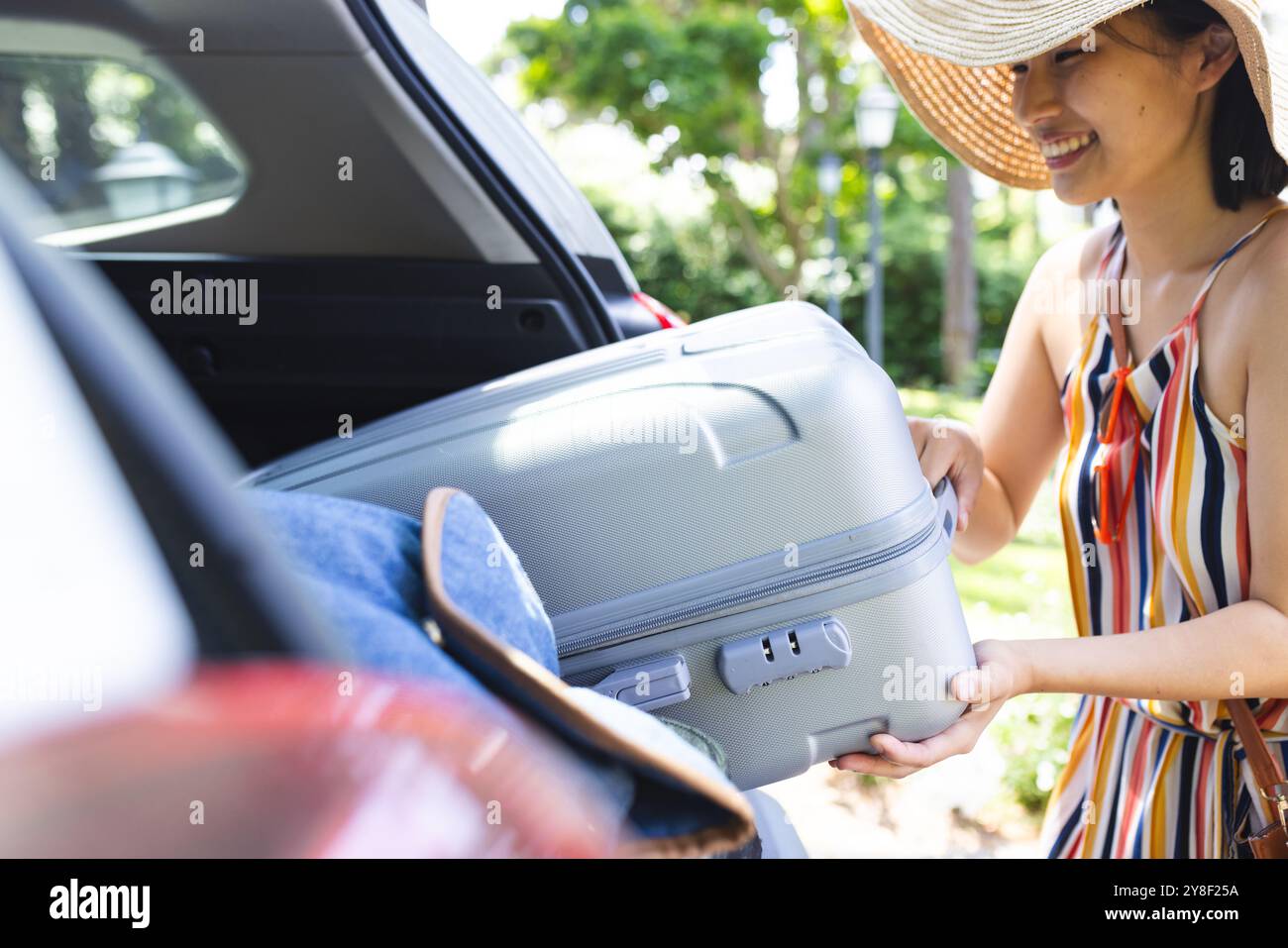 Happy asian woman packing luggage in car in garden at home Stock Photo ...