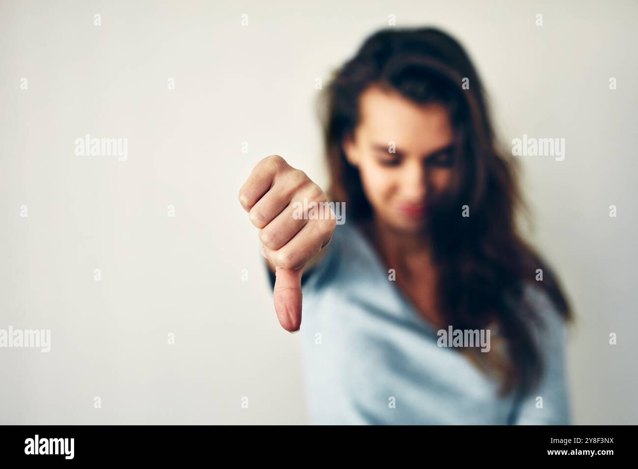 Woman, person and hand with thumbs down in studio for bad review ...