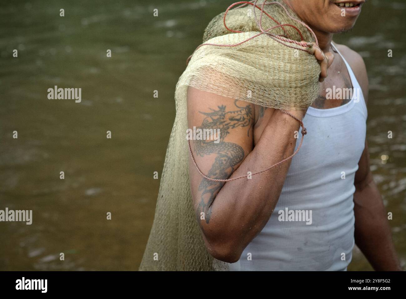 A man carrying a fishing net on riverbank in Sungai Utik, Batu Lintang ...
