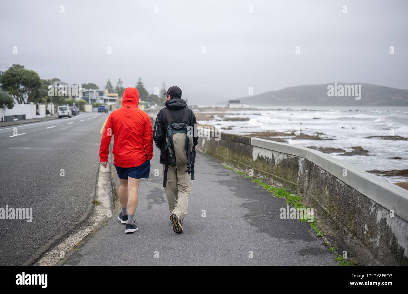 Two people walking on Plimmerton beach on a cold windy day. Wellington ...