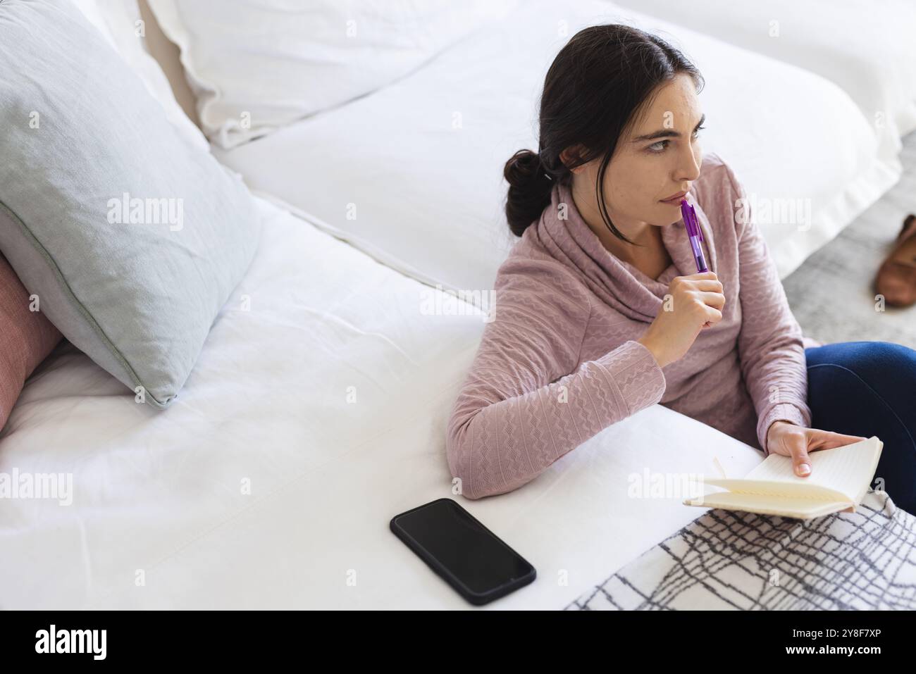 High angle view of caucasian young woman thinking and writing in ...