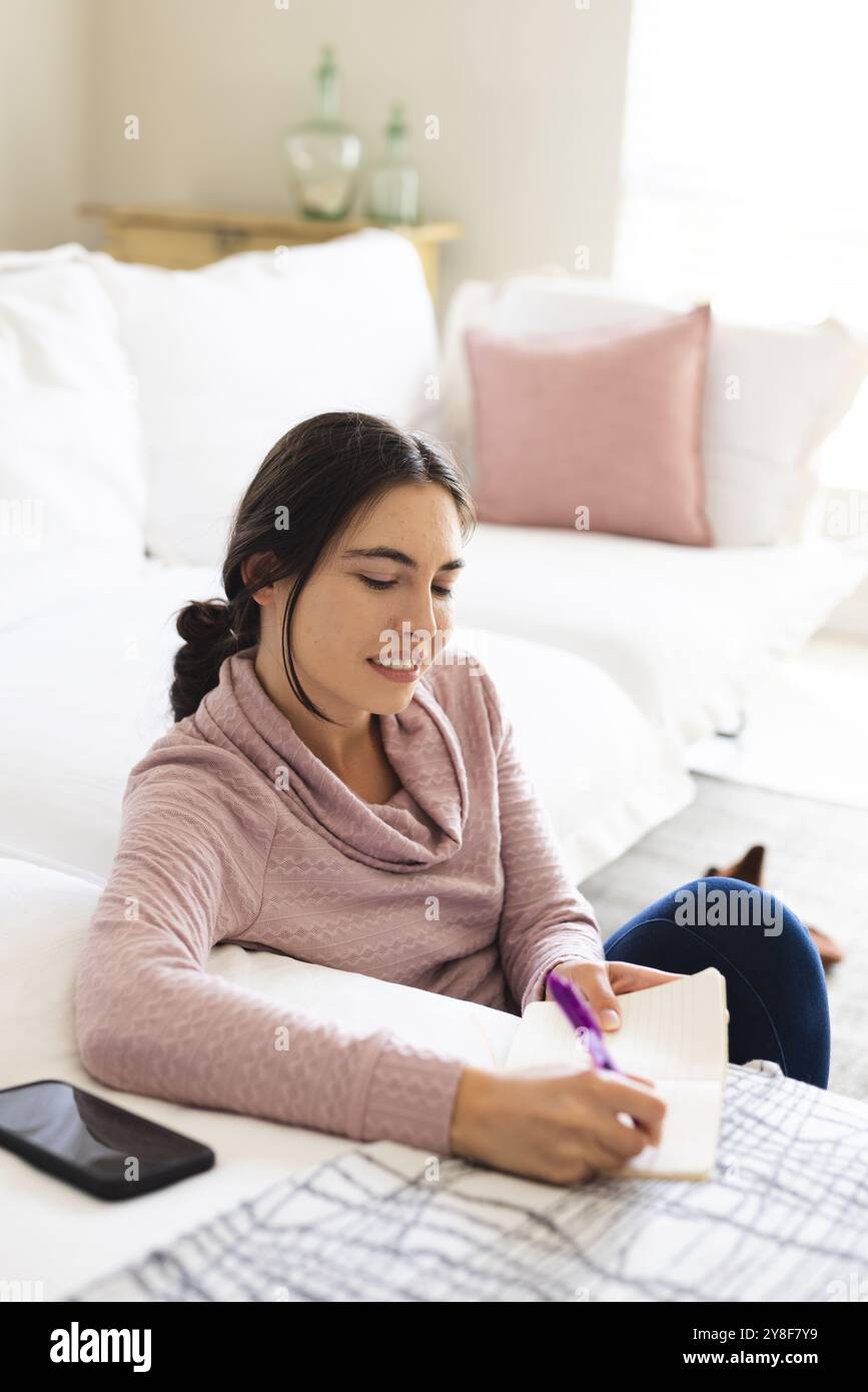 Caucasian beautiful woman thinking and writing in notepad while ...