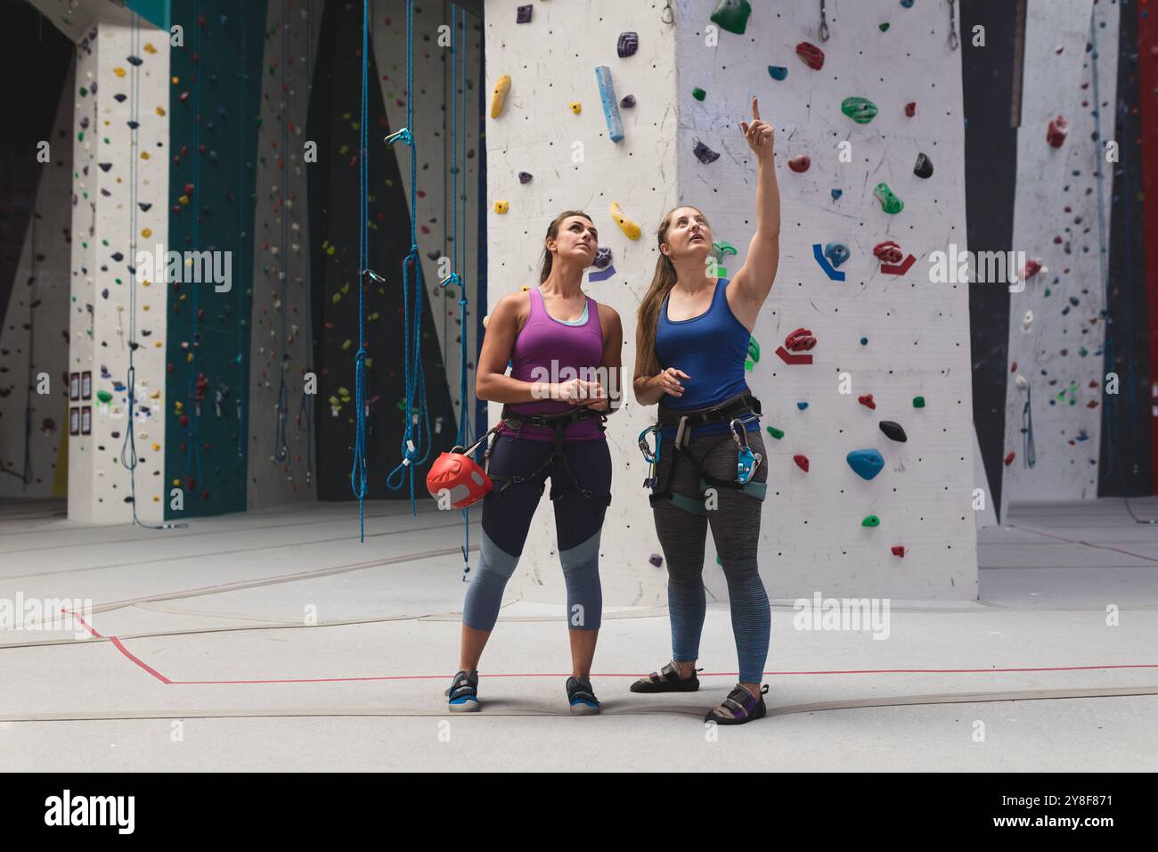 Two happy caucasian women talking and preparing for a climb at indoor ...