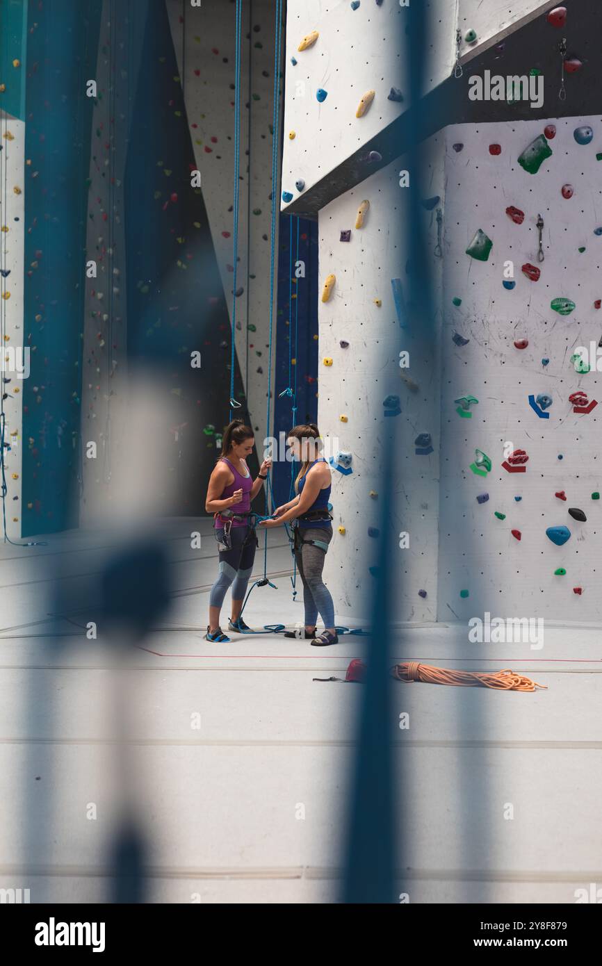 Caucasian female instructor showing woman how to knot a rope to a ...