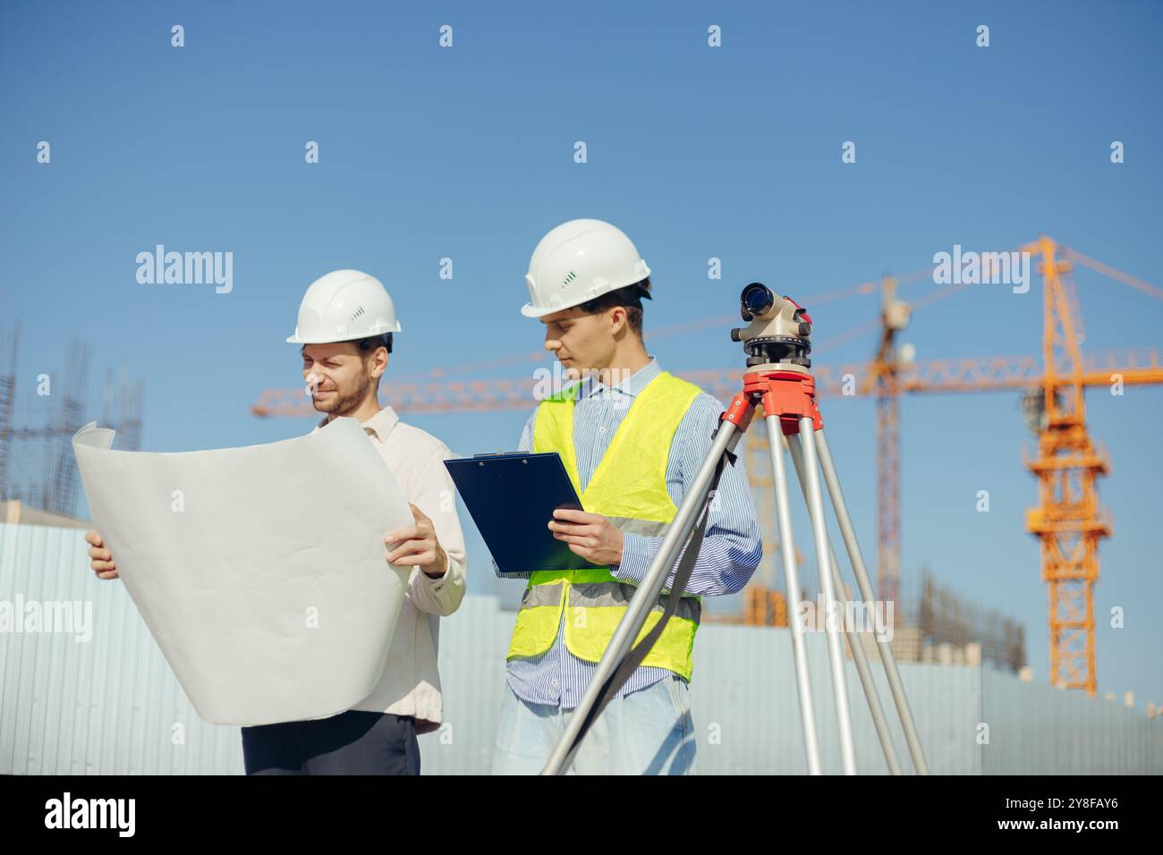 Team of building experts working with drawings with Surveyor level at ...