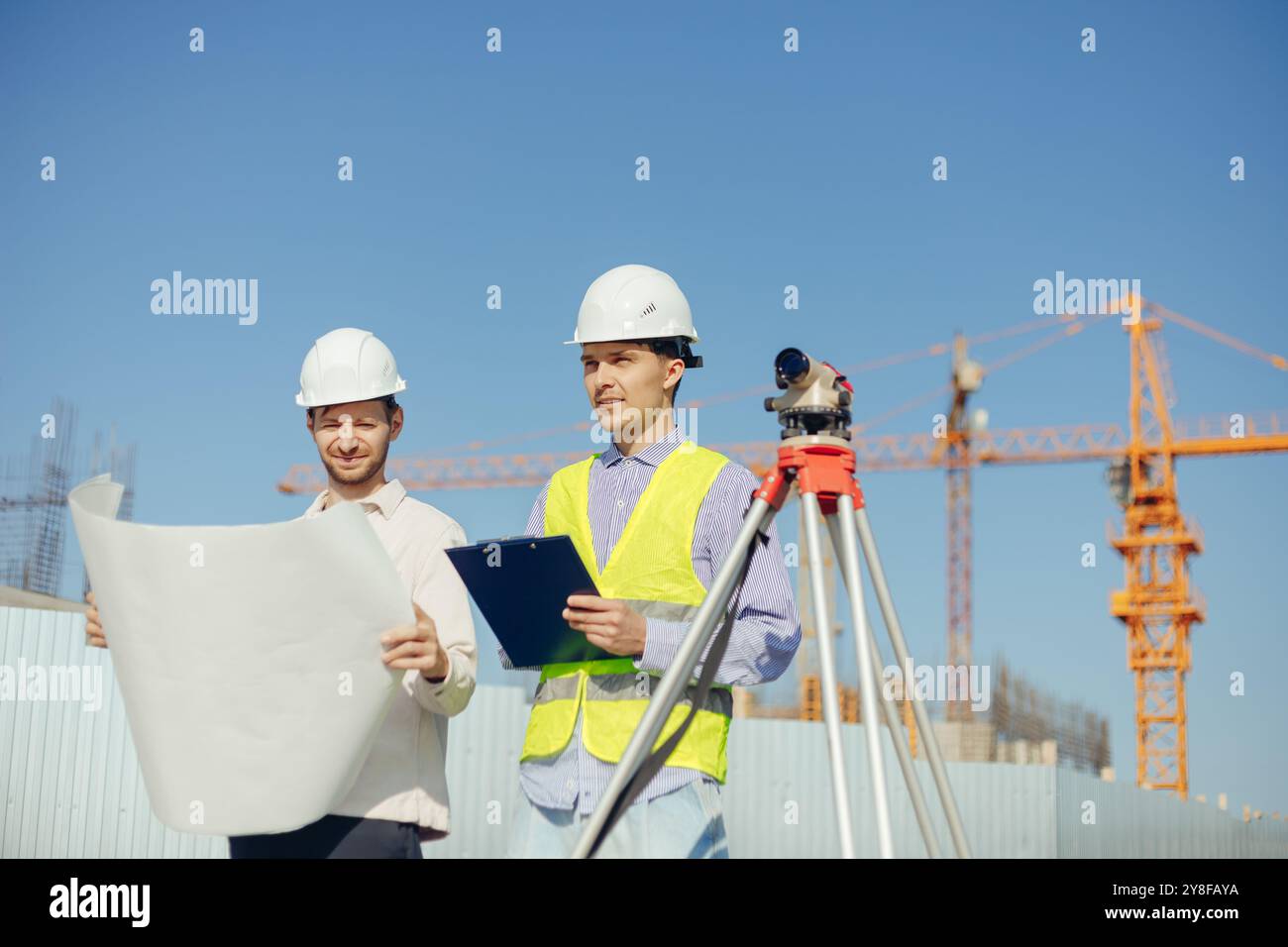 Team of building experts working with drawings with Surveyor level at ...