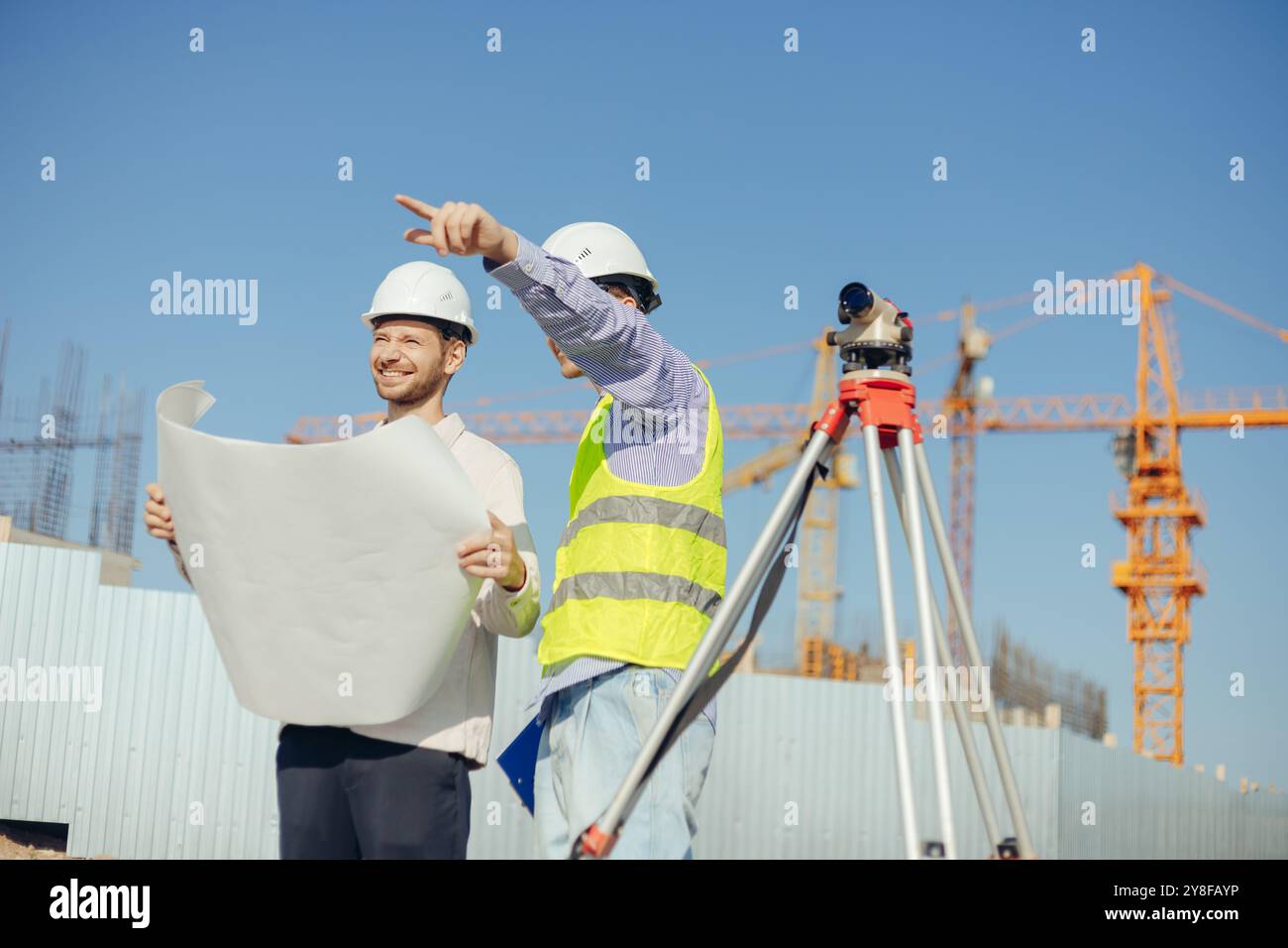 Team of building experts working with drawings with Surveyor level at ...
