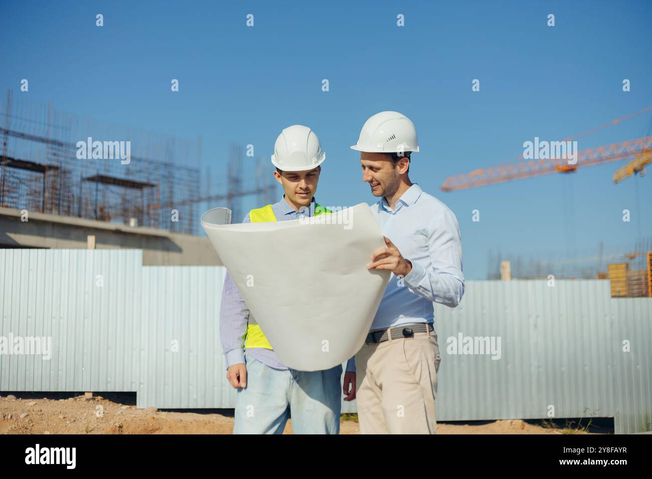 Team of building experts with drawings inspecting new development site ...