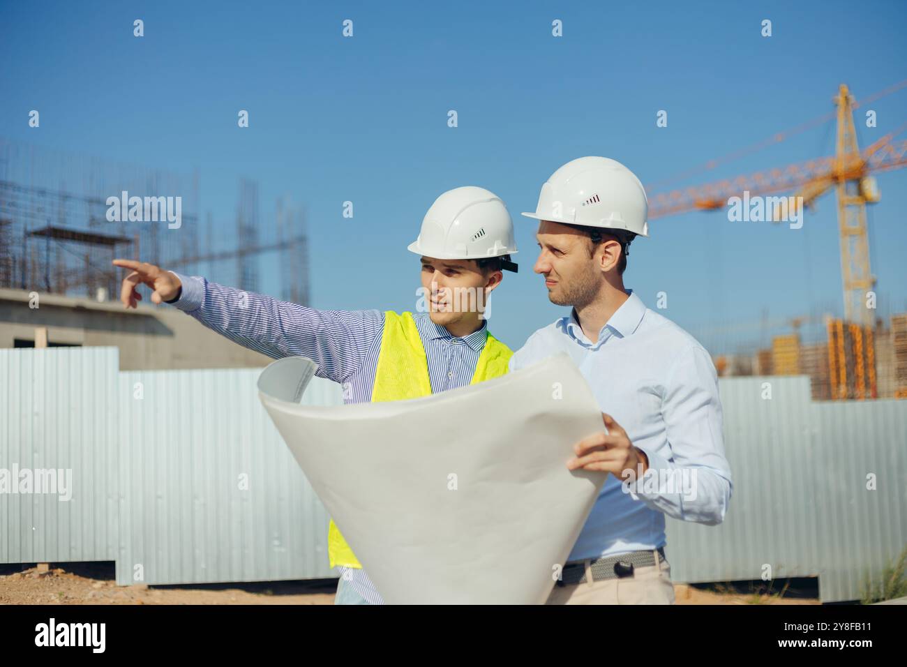 Team of building experts with drawings inspecting new development site ...