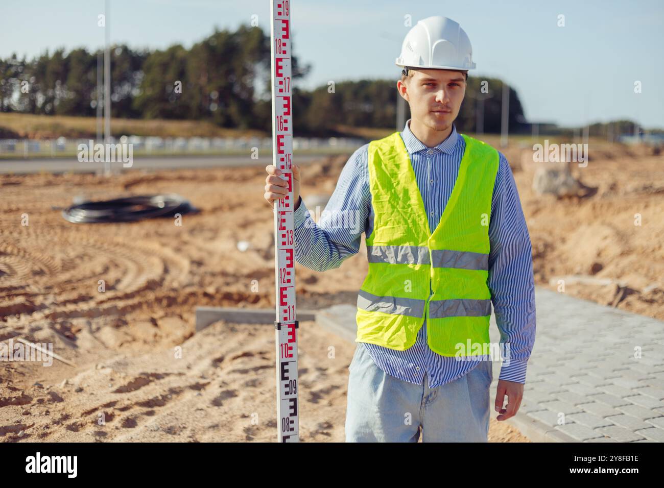 Worker is unfolding leveling rod on construction site Stock Photo - Alamy