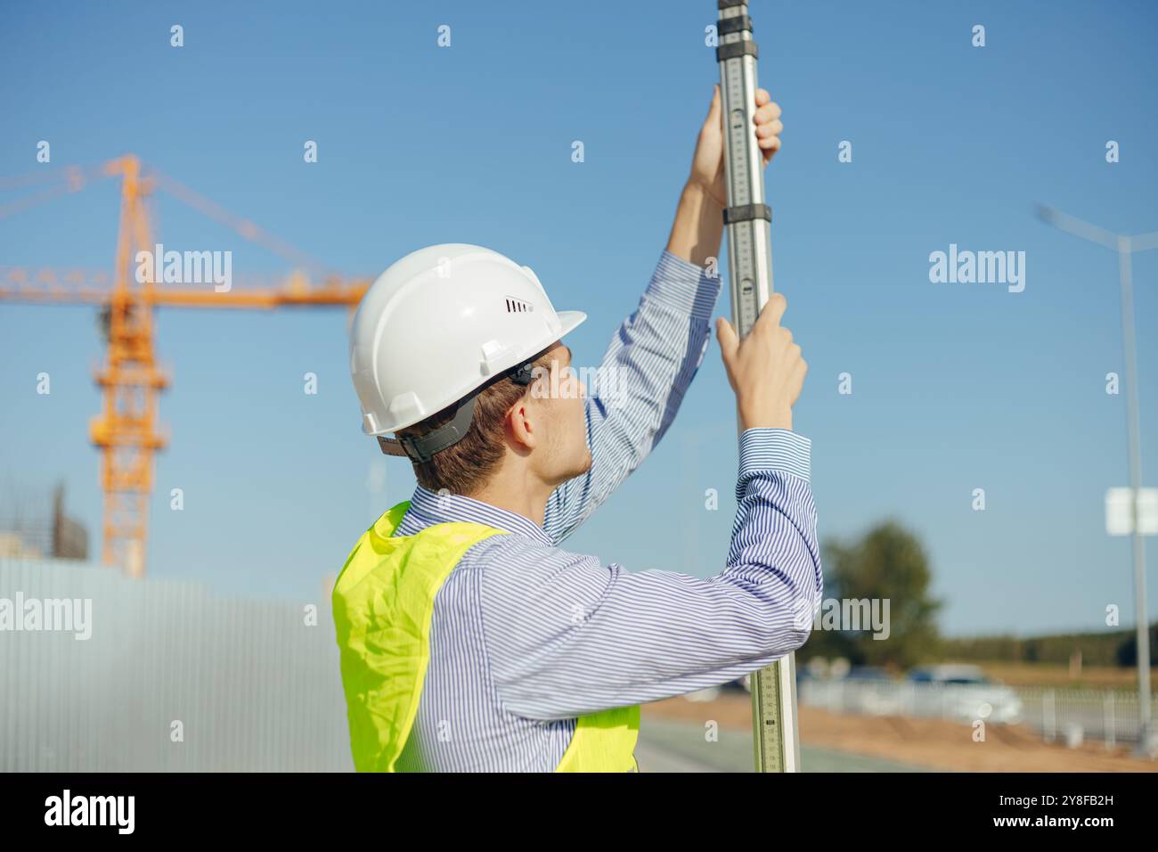 Worker is unfolding leveling rod on construction site Stock Photo - Alamy