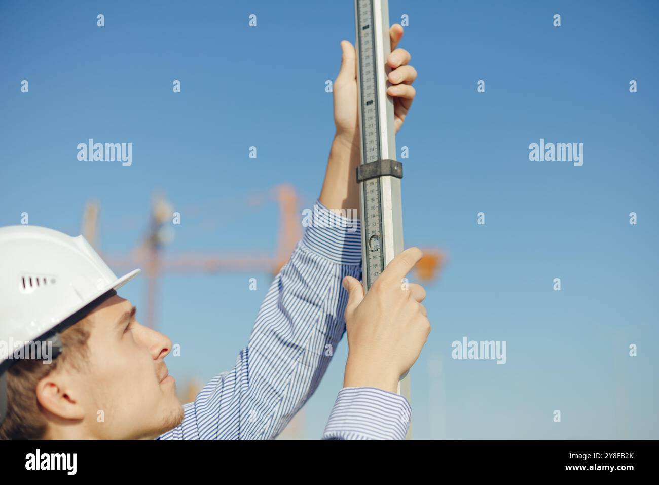 Worker is unfolding leveling rod on construction site Stock Photo - Alamy