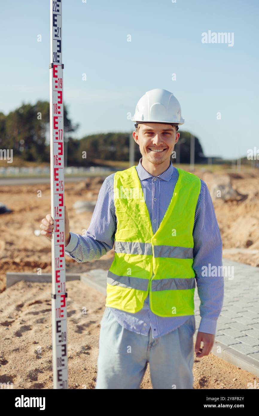 Worker is unfolding leveling rod on construction site Stock Photo - Alamy